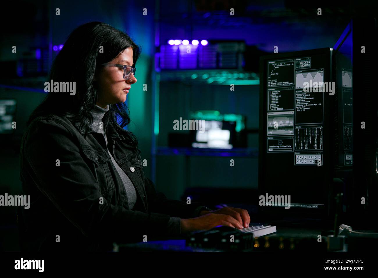 Low Key Lighting Shot Of Female Computer Hacker Sitting In Front Of ...