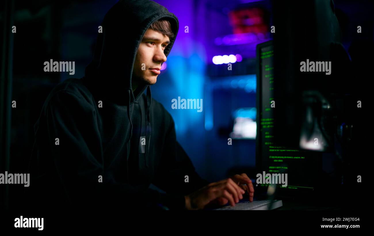 Low Key Lighting Shot Of Male Computer Hacker Sitting In Front Of Screens Breaching Cyber ...