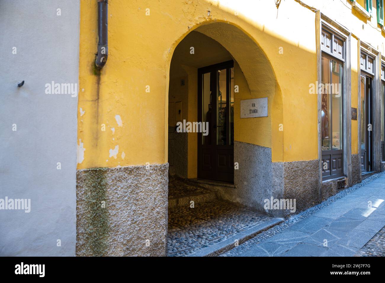 A bright yellow building showcases a visually striking dark door that ...