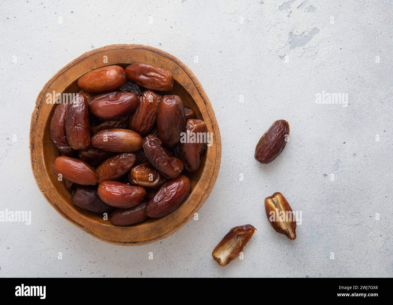 Wooden bowl of dried sweet brown dates on light background Stock Photo ...