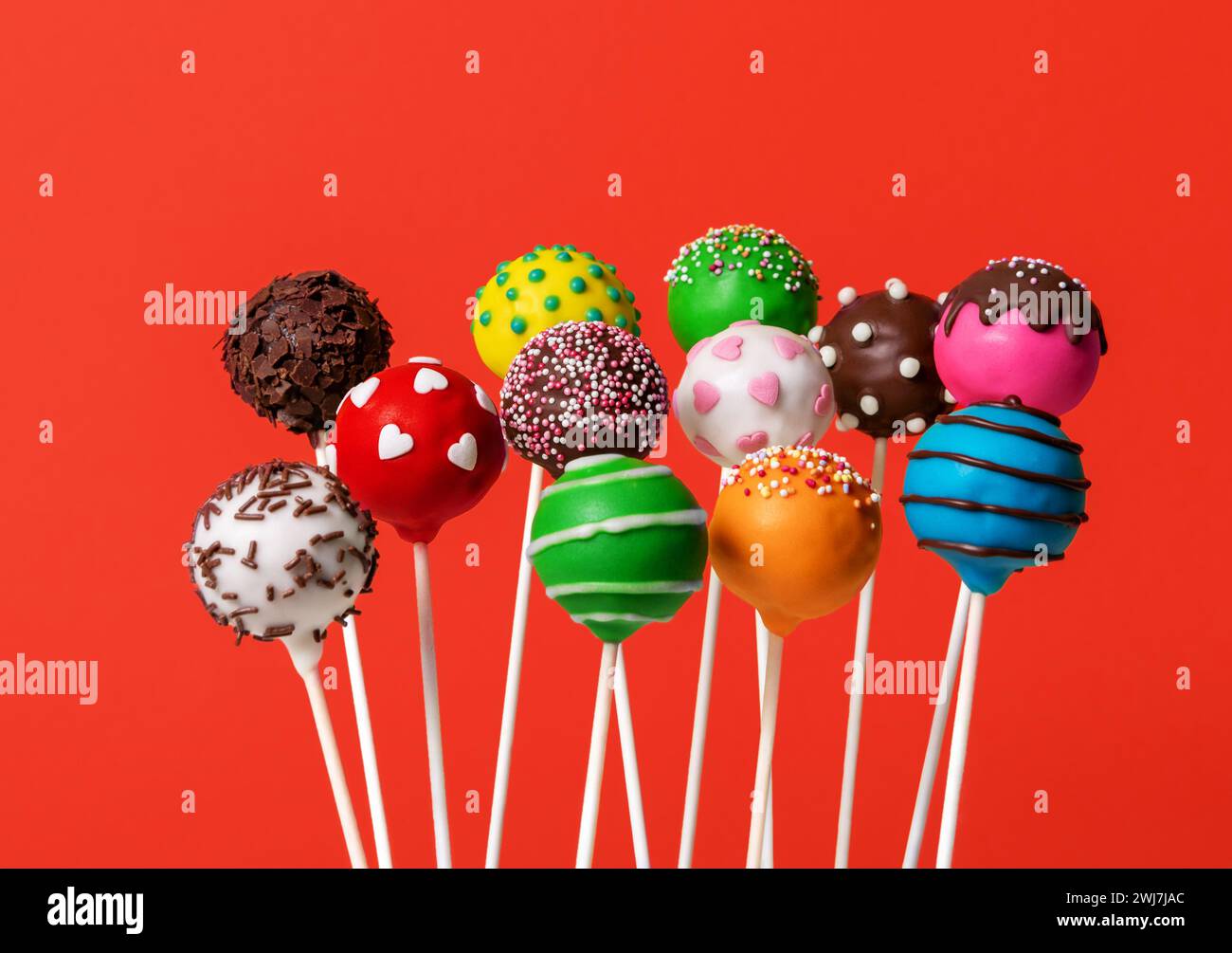 Homemade cake pops with various icings colors, minimalist on a red ...