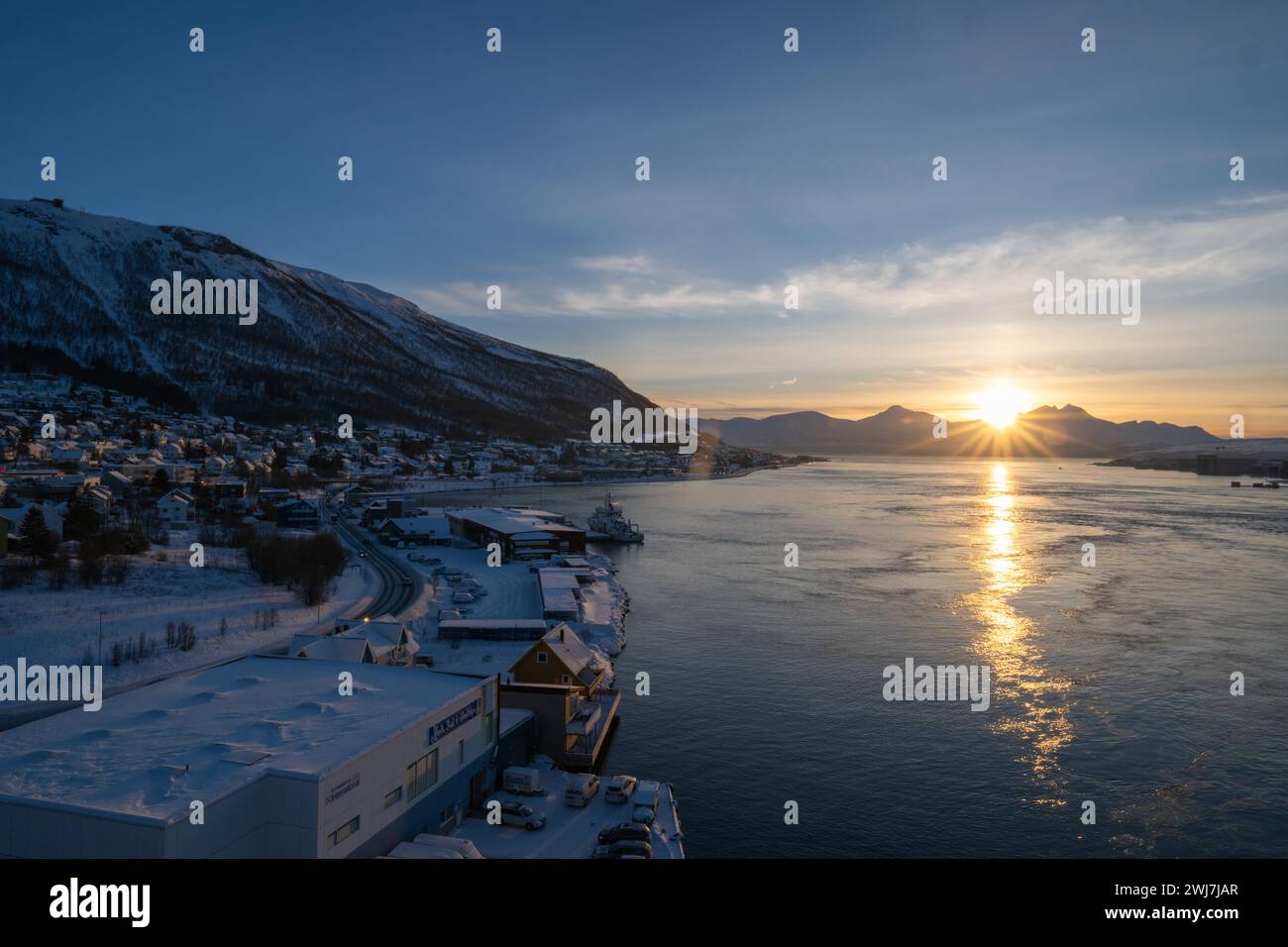 The sun setting behind the mountains and casting a golden reflection ...