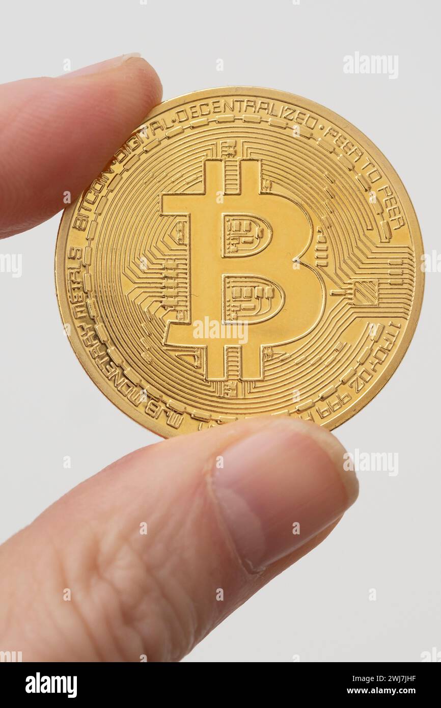 Bitcoin coin between fingers Stock Photo - Alamy