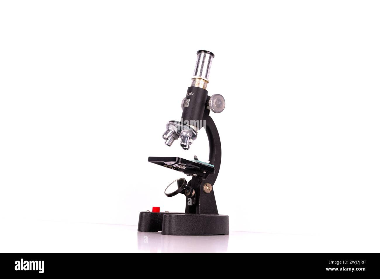 an old microscope stands isolated on a white background on a white ...