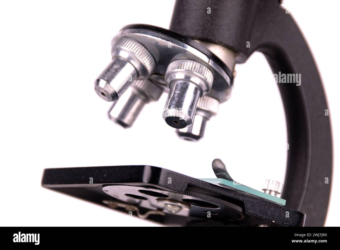 an old microscope stands isolated on a white background on a white ...