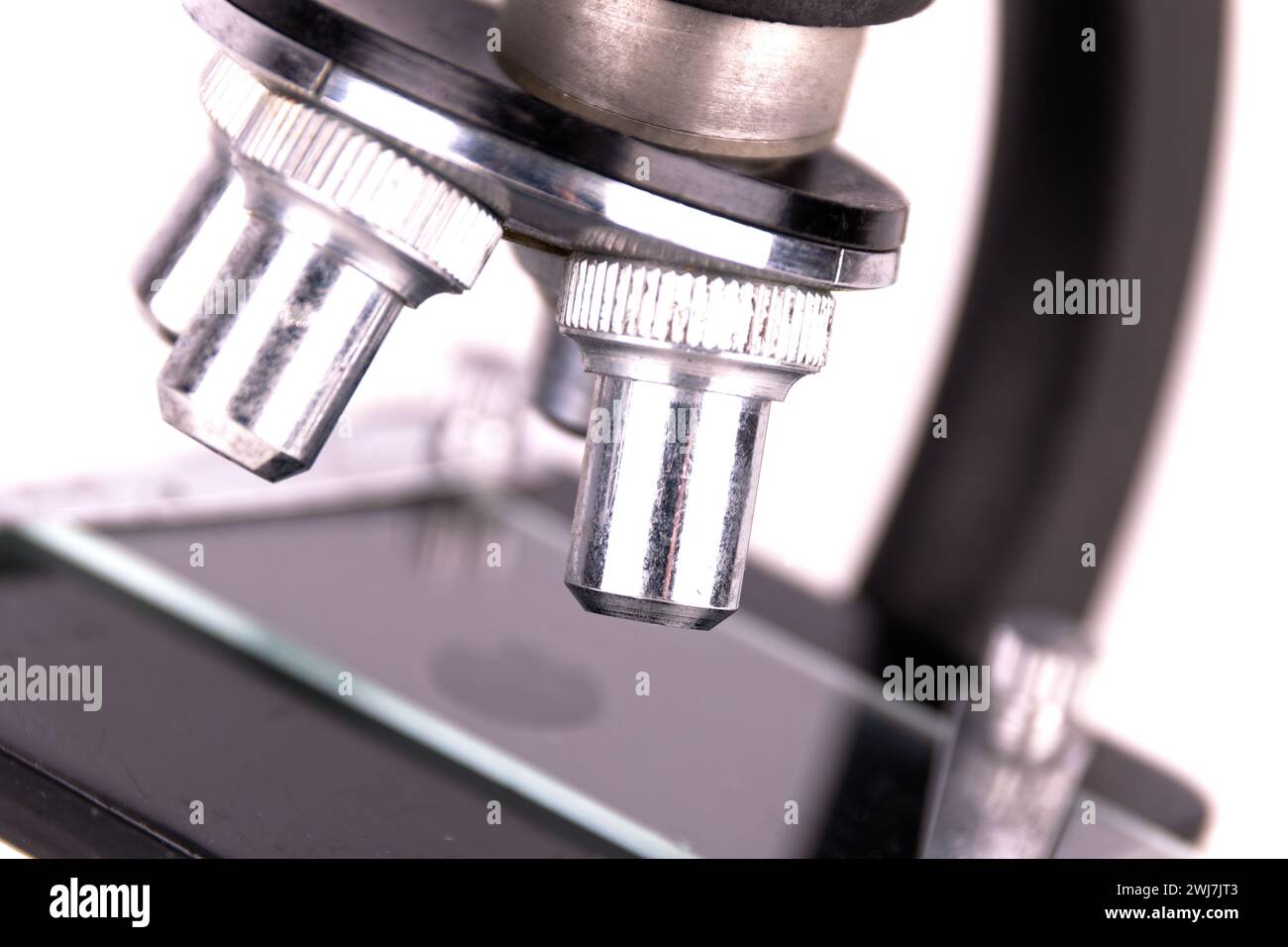 an old microscope stands isolated on a white background on a white ...