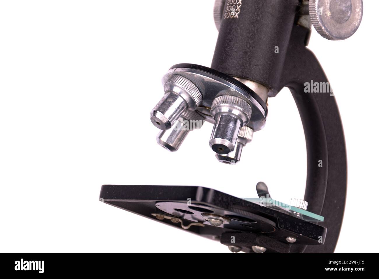an old microscope stands isolated on a white background on a white ...