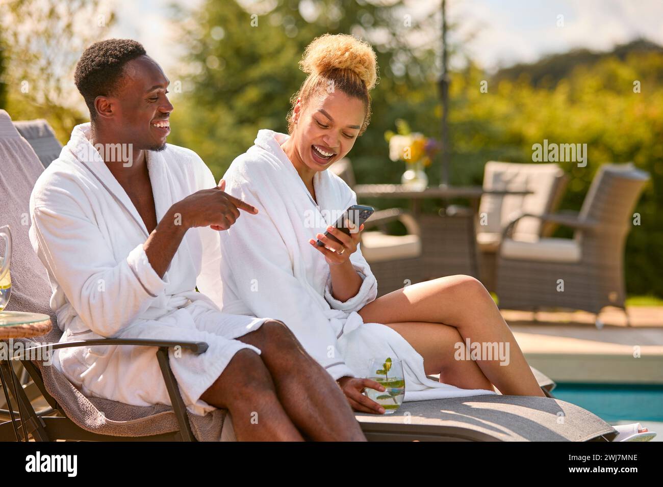 Couple In Robes Outdoors On Loungers By Pool On Spa Day Looking At ...