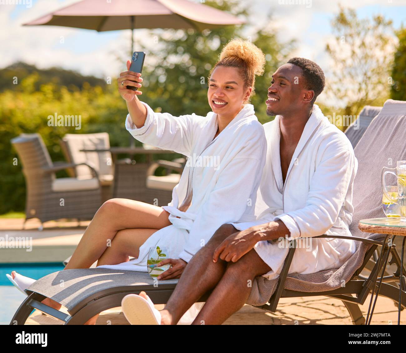 Couple In Robes Outdoors On Loungers By Pool On Spa Day Posing For ...