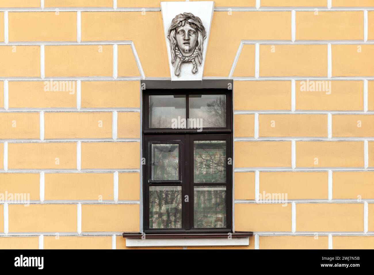 Yellow wall with sculpture decor above the window, front view. Classic ...