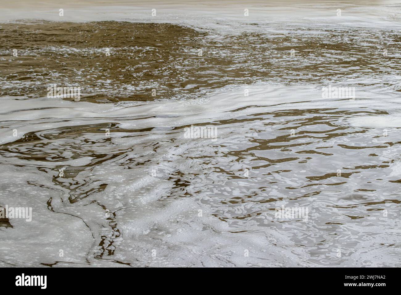 Stream of dirty flowing water covered with foam. Water and environment ...