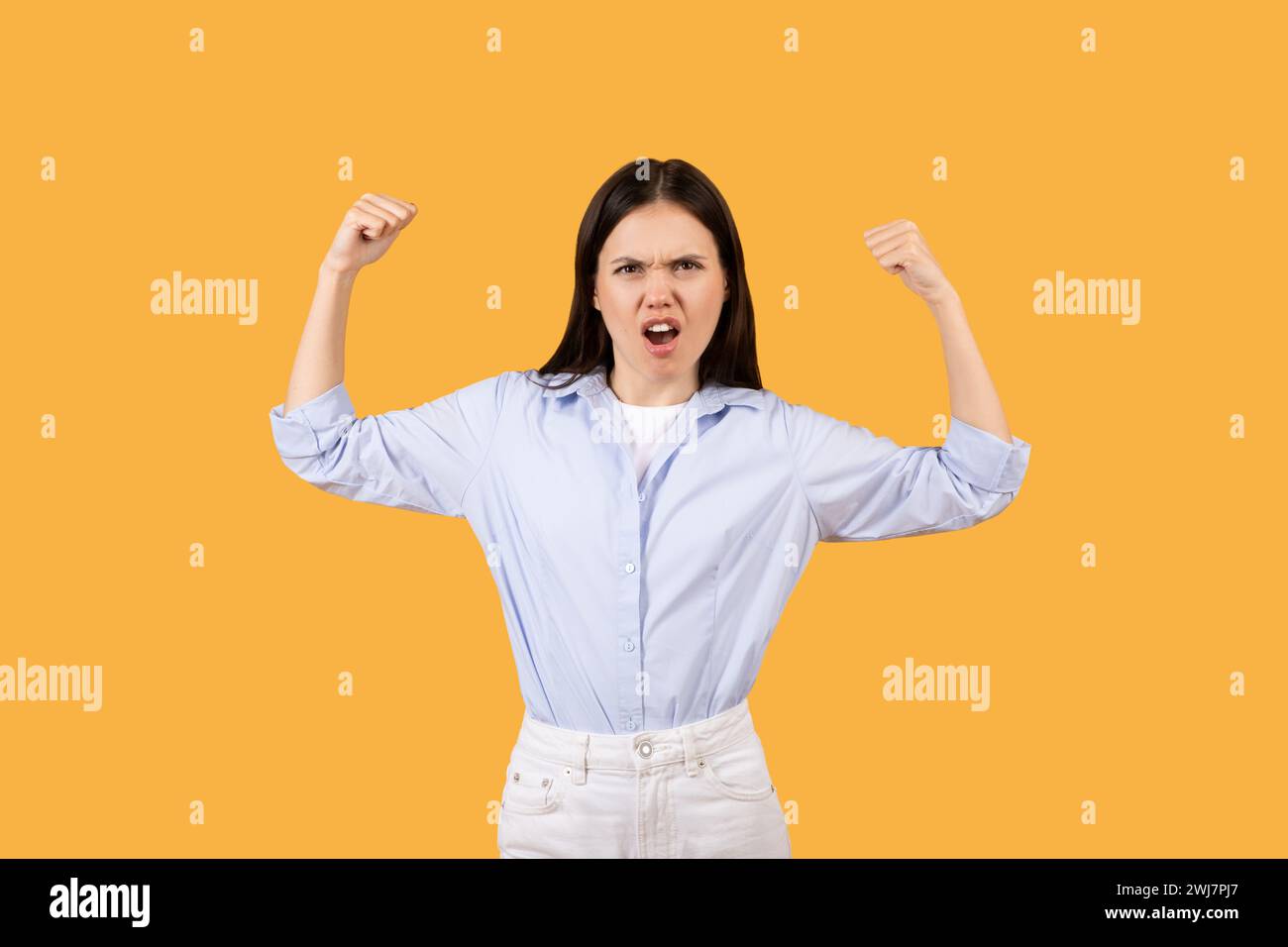 Angry lady student showing strength gesture, yellow backdrop Stock ...