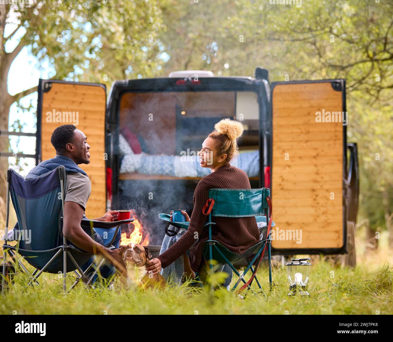 Rear View Of Couple Camping In Countryside With RV Drinking Coffee By ...