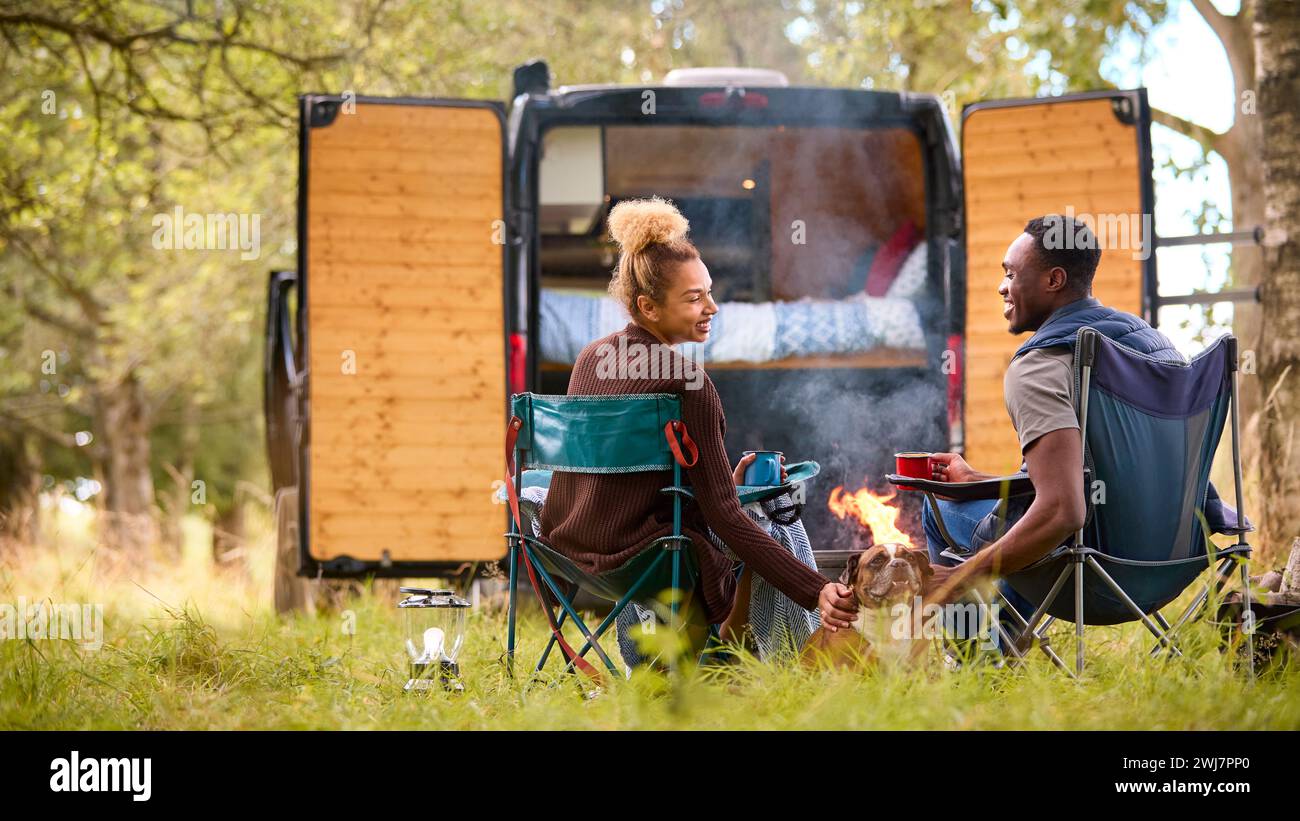 Rear View Of Couple Camping In Countryside With RV Drinking Coffee By ...