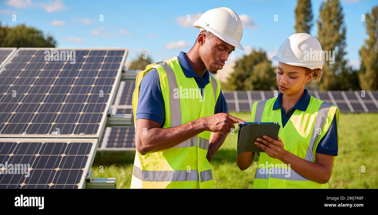 Male And Female Engineers With Digital Tablet Inspecting Solar Panels Generating Renewable ...