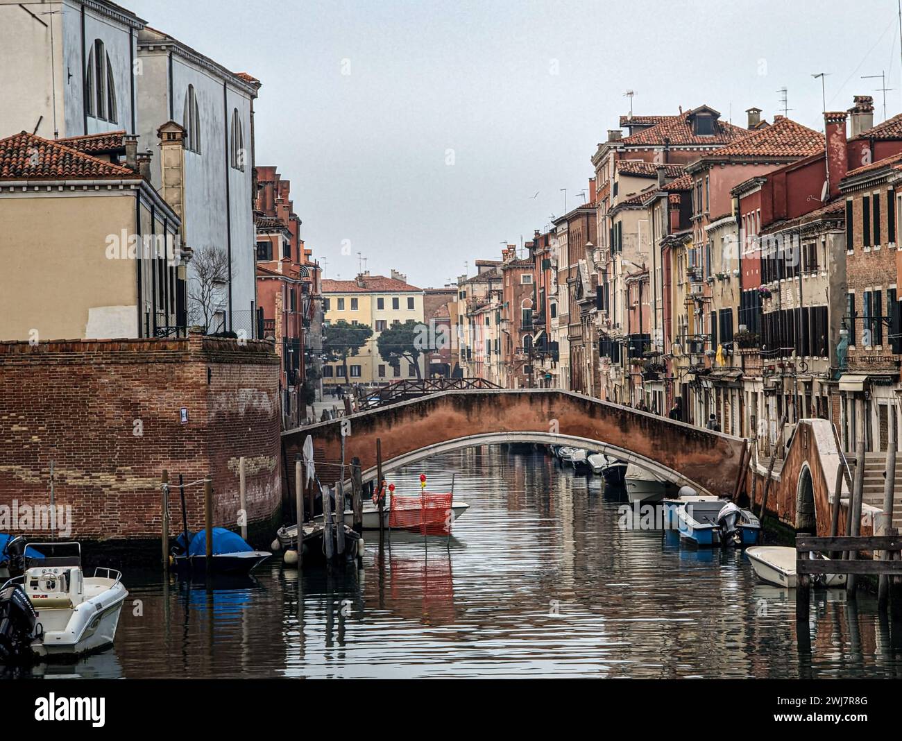 Boats gently float beneath a canal bridge in Venice, Italy Stock Photo ...