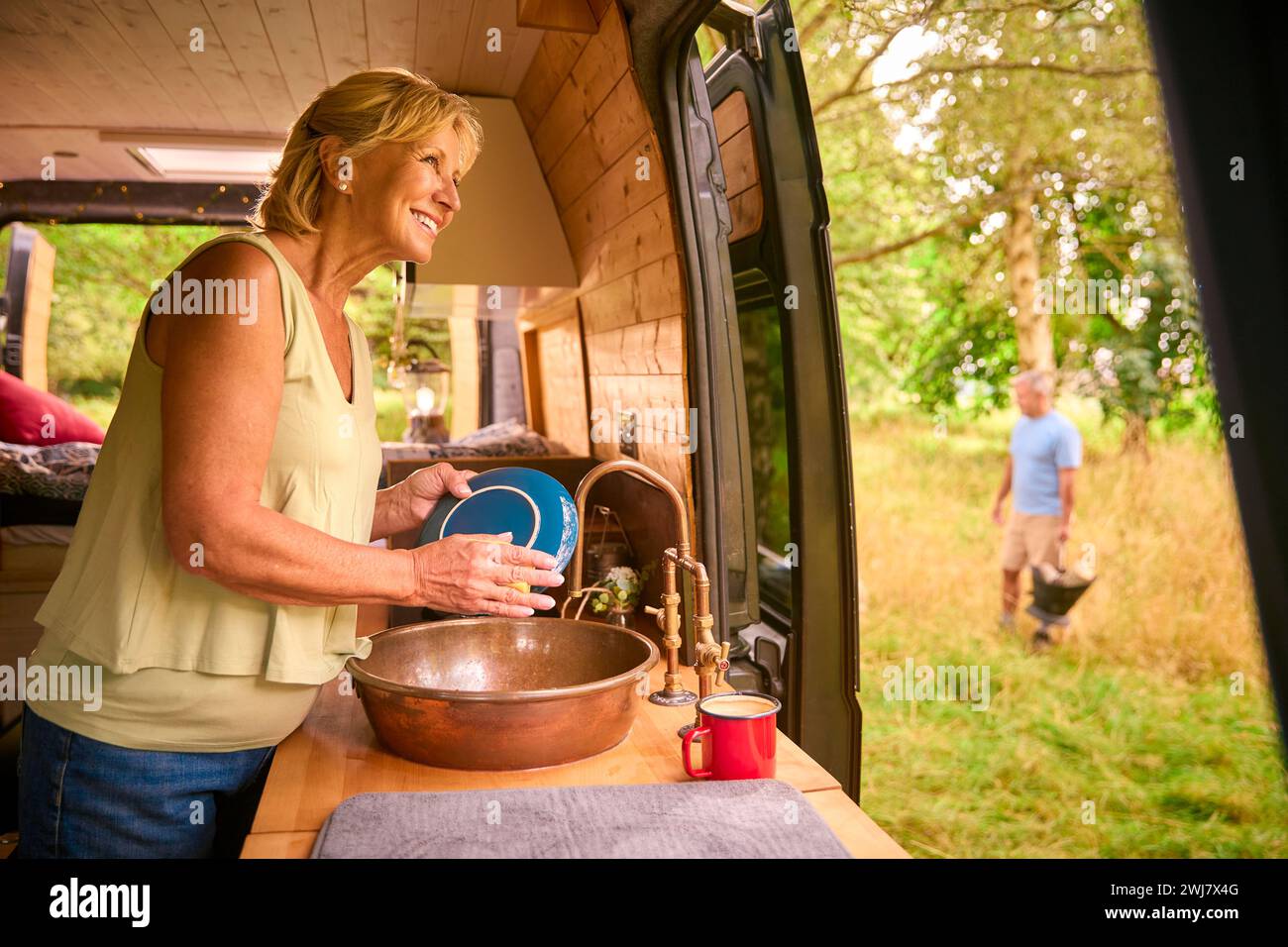 Senior Couple Enjoying Camping In Countryside Relaxing Inside RV And Doing Chores Together Stock ...