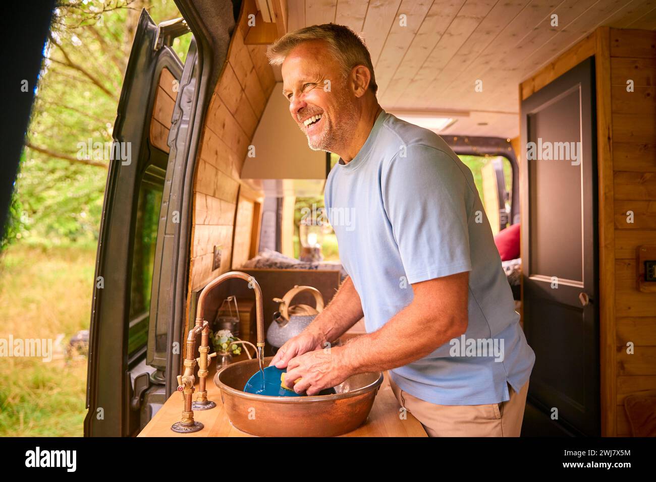 Senior Man Enjoying Camping In Countryside Relaxing Inside RV And Doing ...