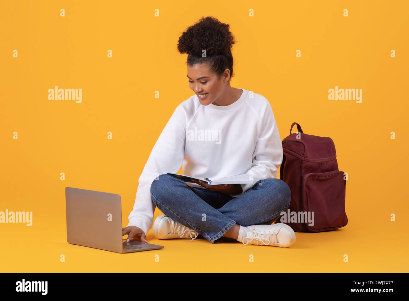 Smiling Young Black Female Student Using Laptop And Taking Notes In ...