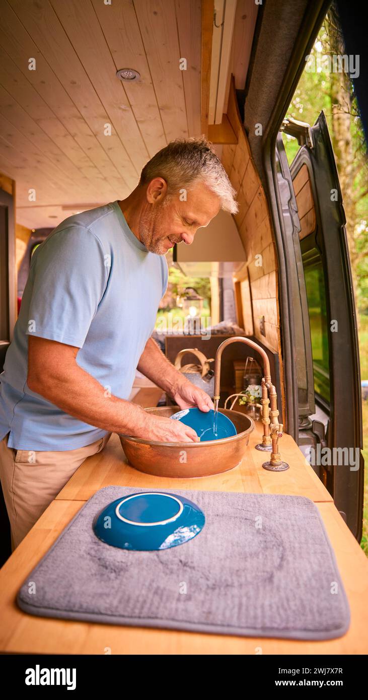Senior Man Enjoying Camping In Countryside Relaxing Inside RV And Doing ...