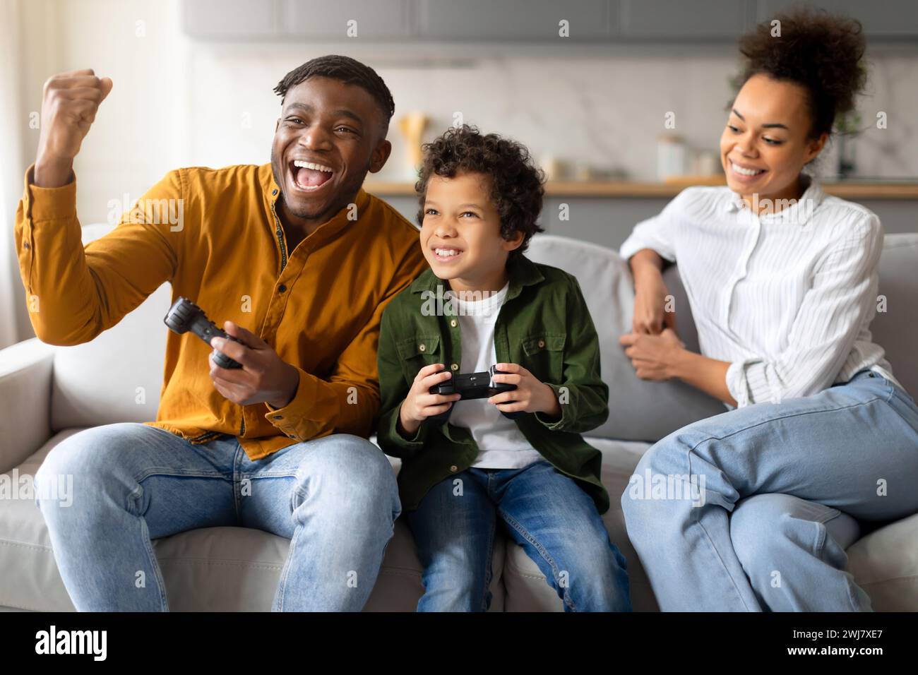 Excited black family playing video games together, joyous victory ...