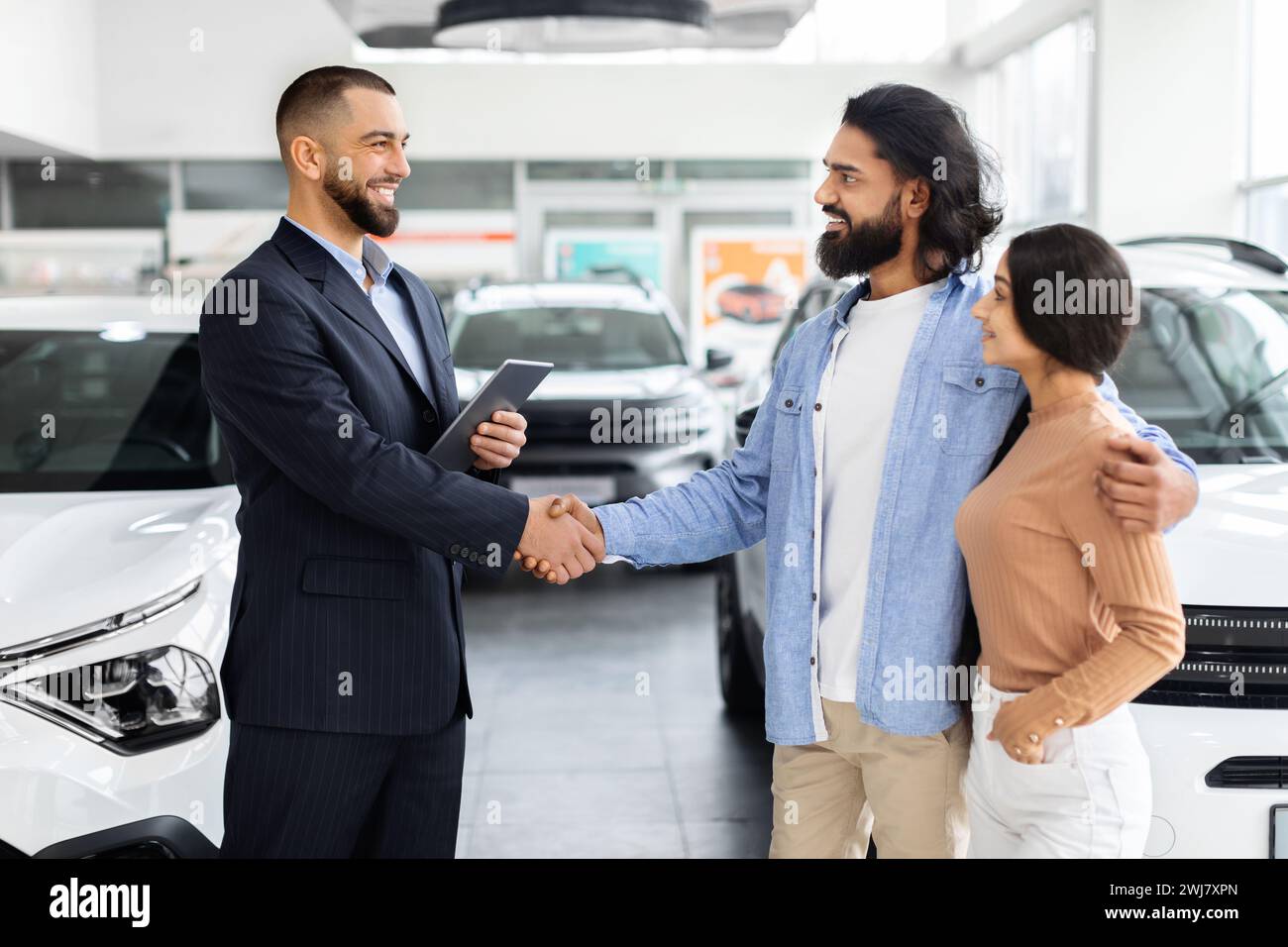 Handsome auto salesman shaking indian guy customer hand Stock Photo - Alamy