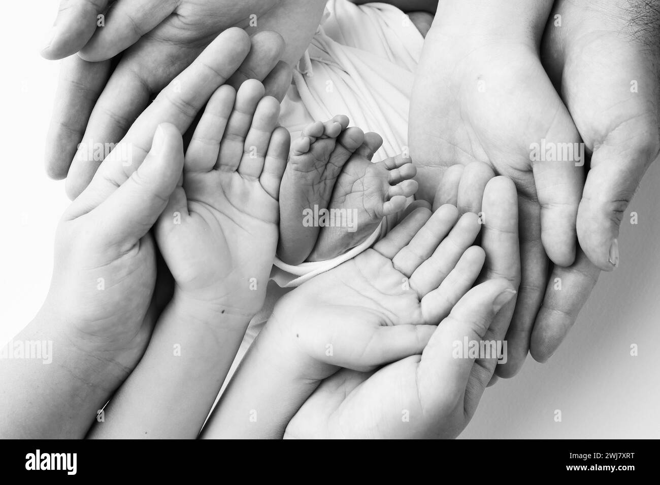 The palms of the father, the mother are holding the foot of the newborn ...