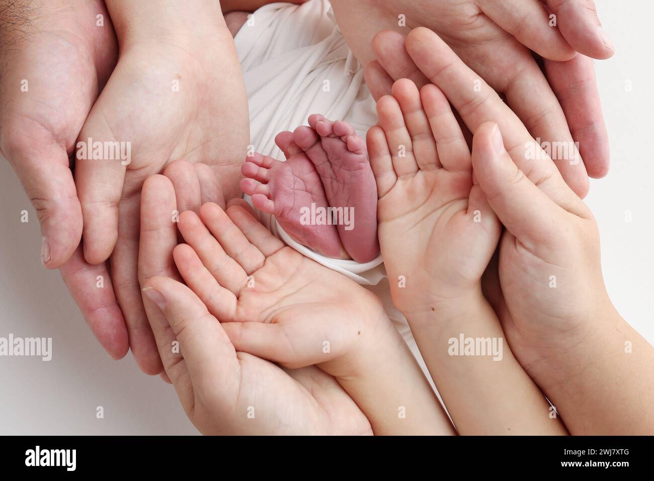 The palms of the father, the mother are holding the foot of the newborn ...