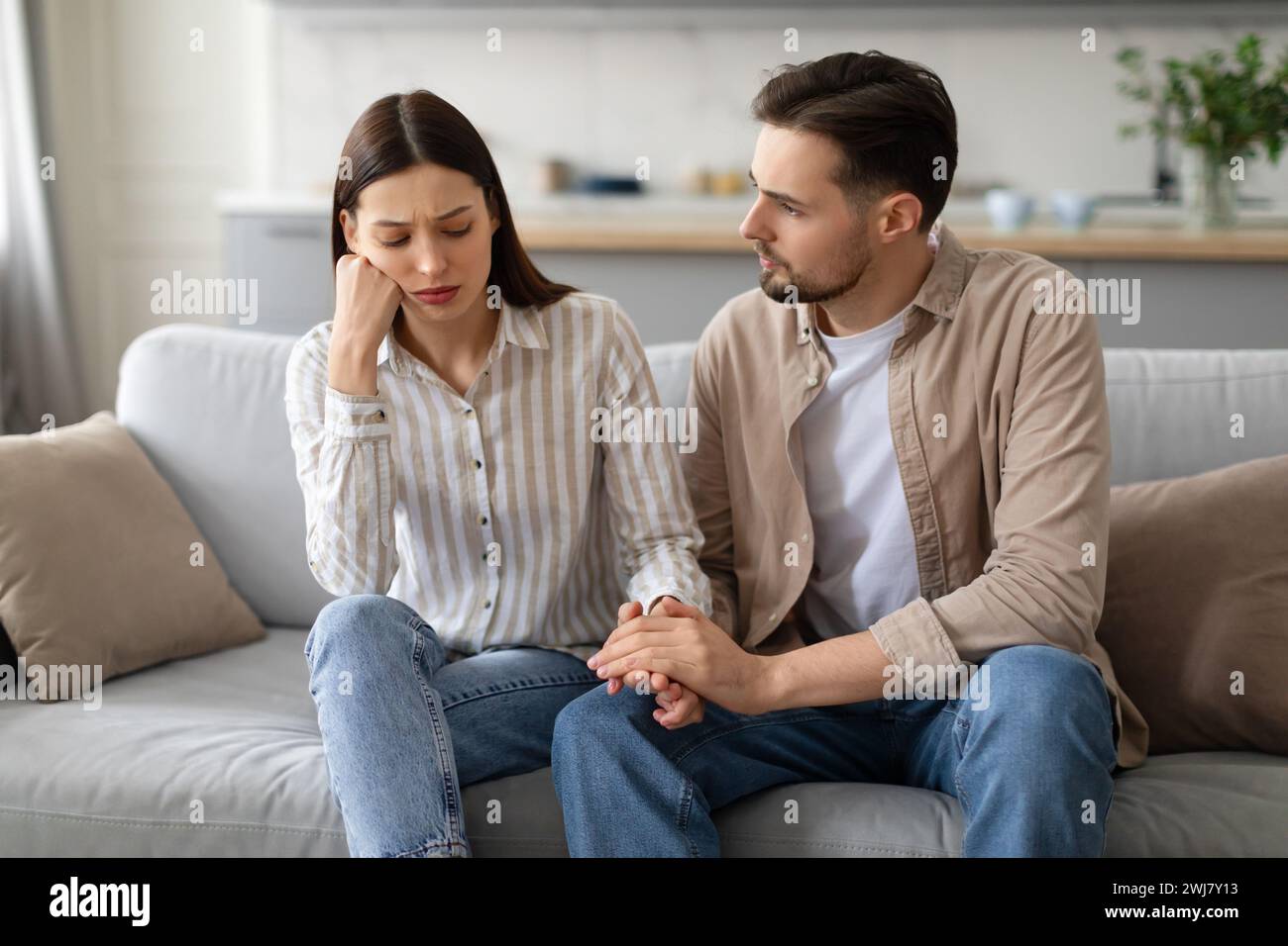 Concerned young man comforting upset woman on couch Stock Photo - Alamy