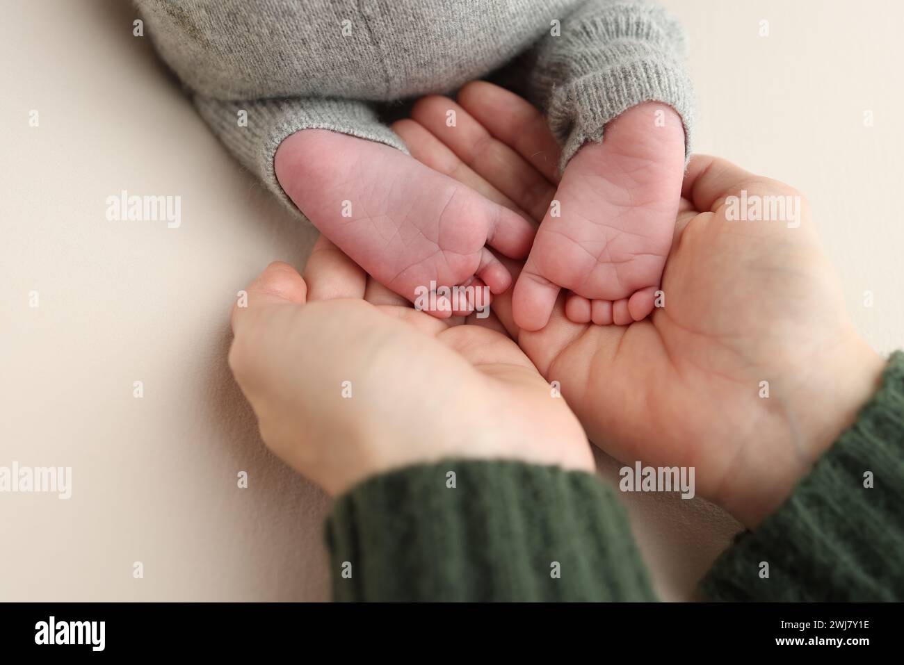 The palms of the father, the mother are holding the foot of the newborn ...