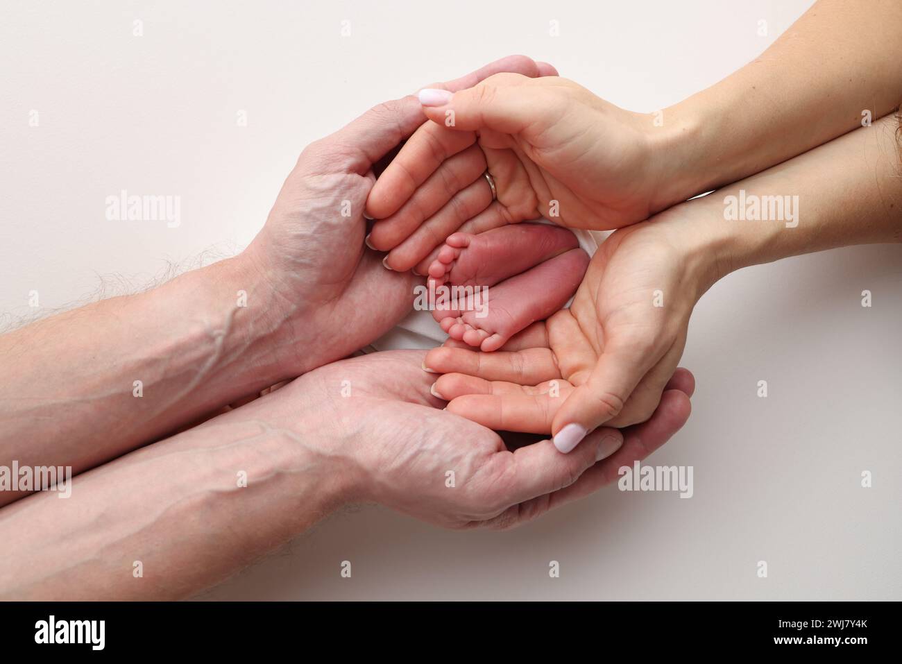The palms of the father, the mother are holding the foot of the newborn ...