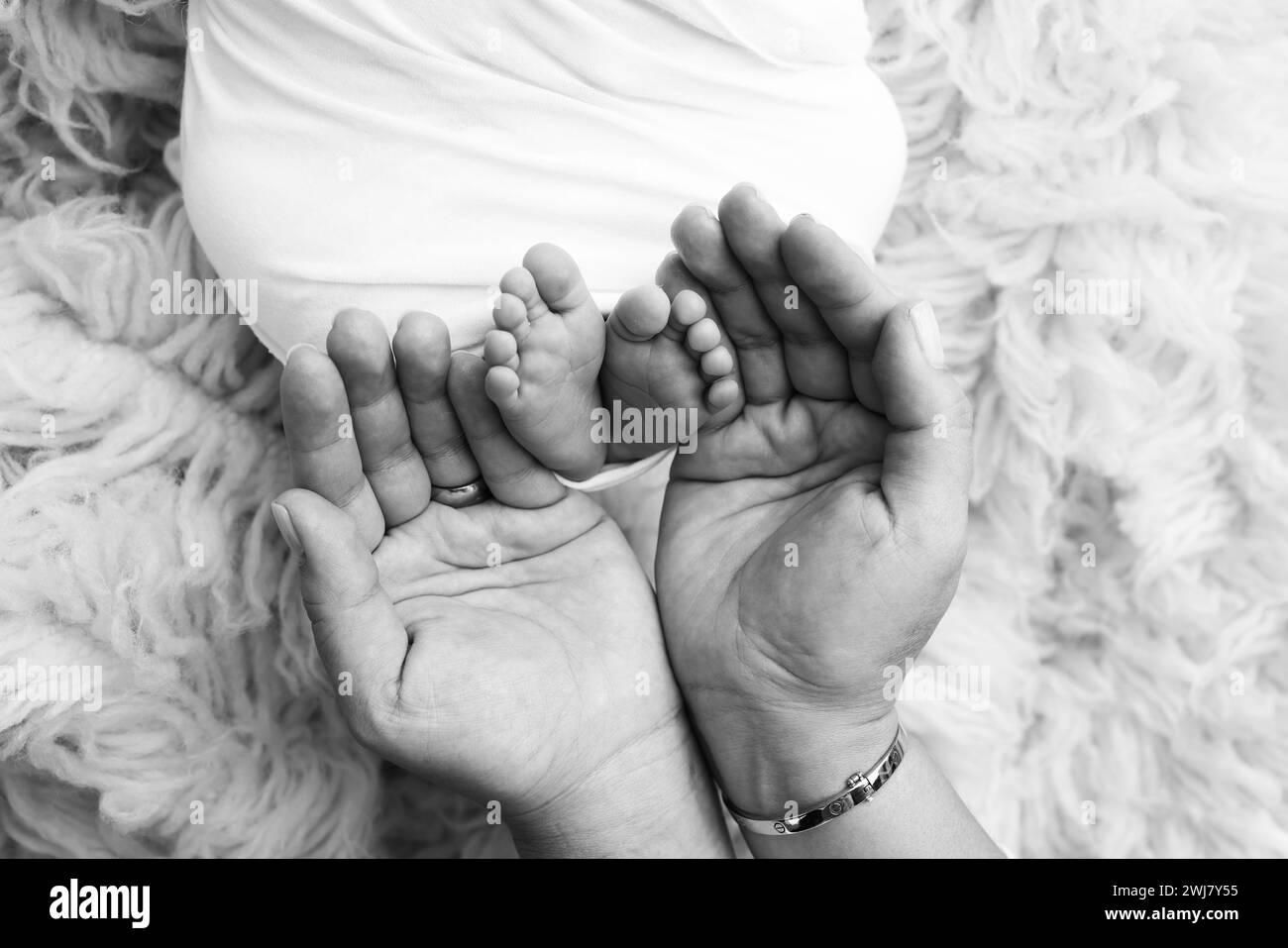 The palms of the father, the mother are holding the foot of the newborn ...