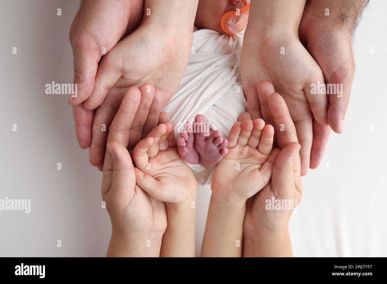 The palms of the father, the mother are holding the foot of the newborn ...