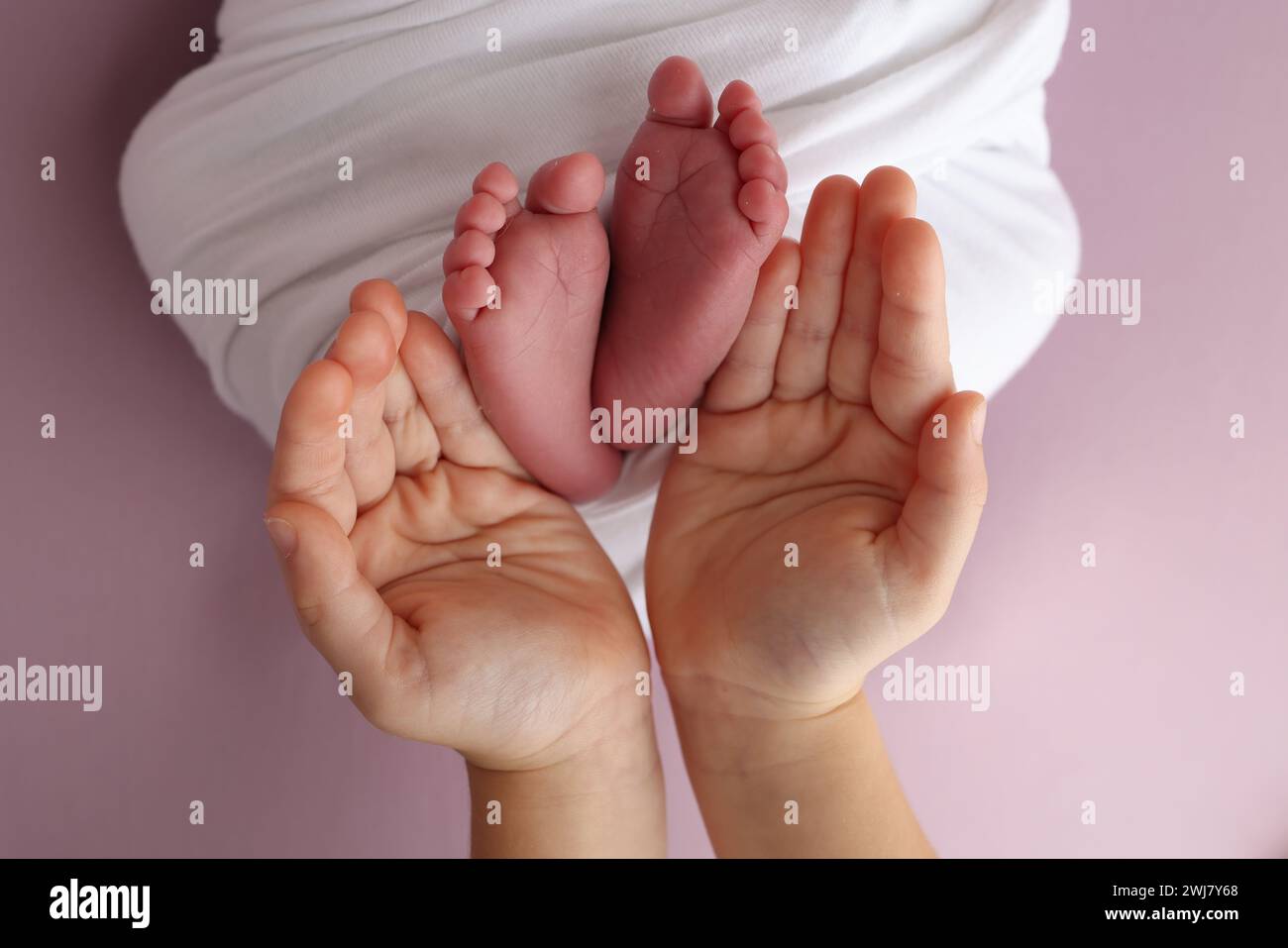 The palms of the father, the mother are holding the foot of the newborn ...