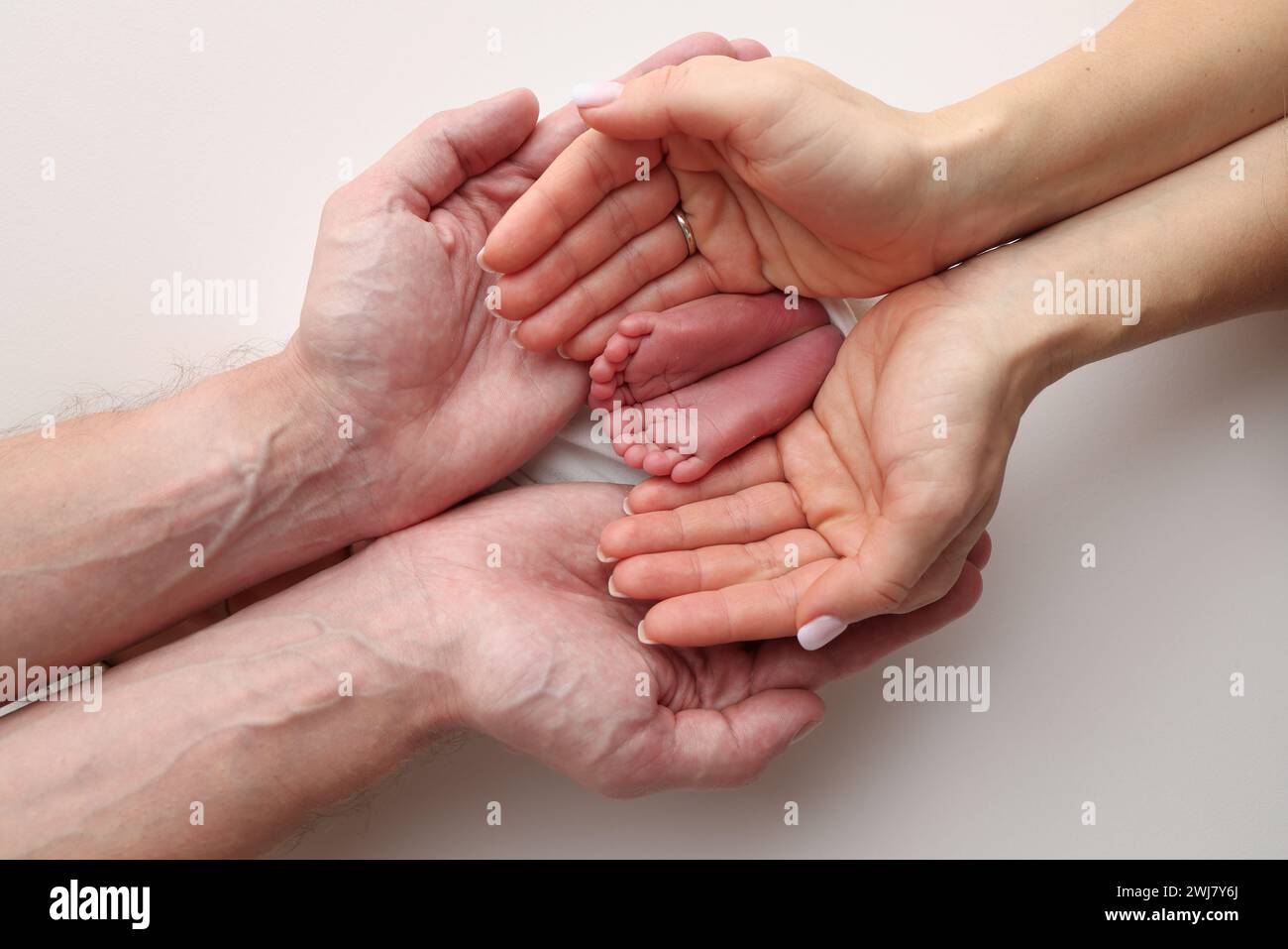 The palms of the father, the mother are holding the foot of the newborn ...