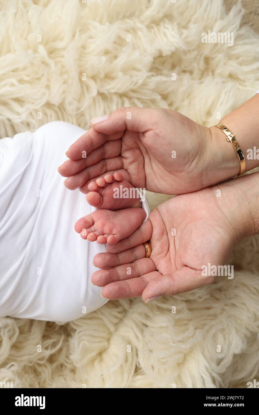The palms of the father, the mother are holding the foot of the newborn ...