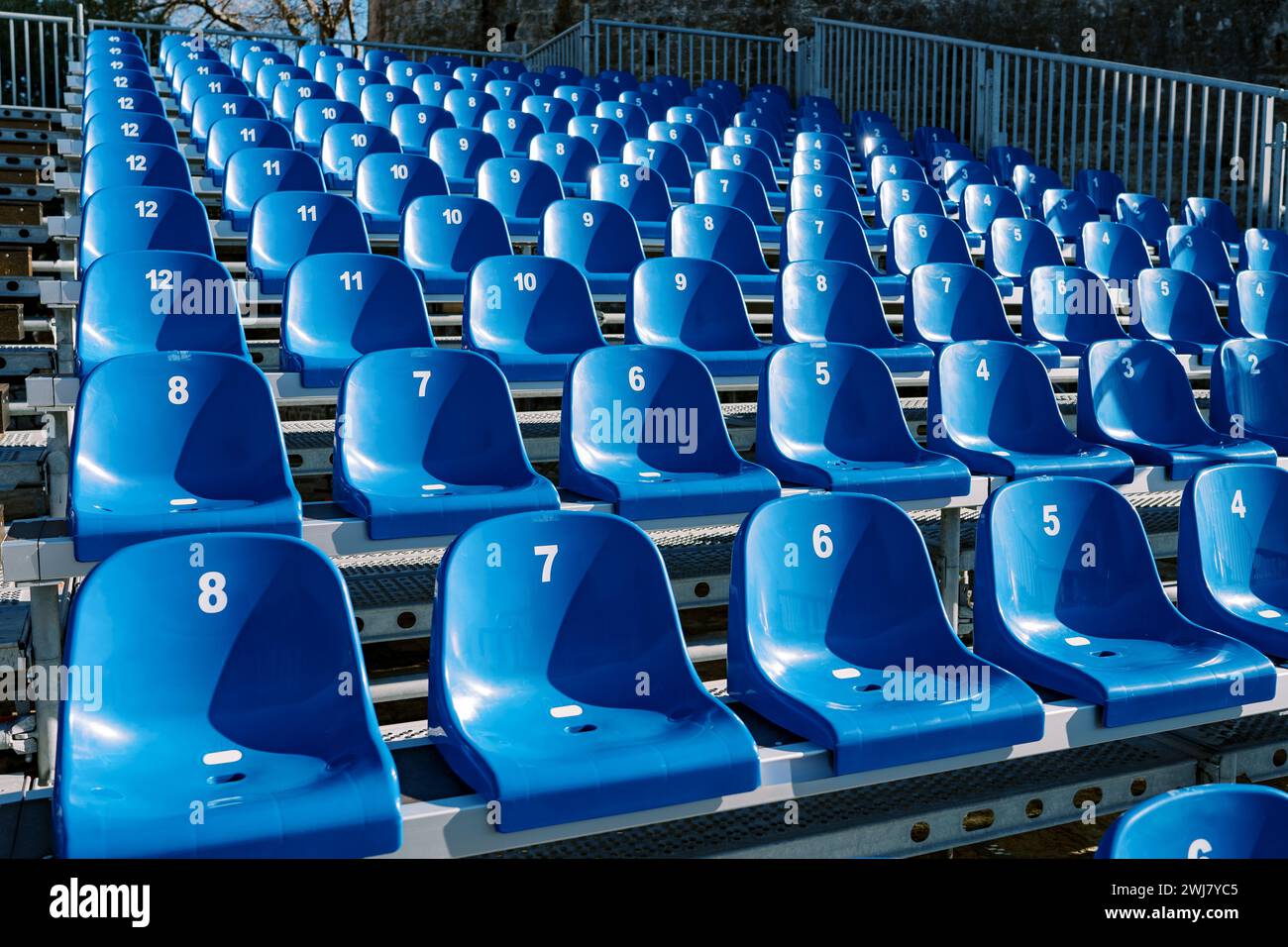 Rows of blue chairs arranged in tiers and steps surrounded by a metal ...