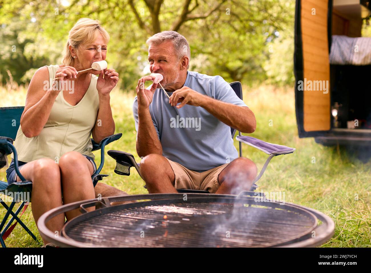 Senior Couple Camping In Countryside With RV Toasting And Eating ...