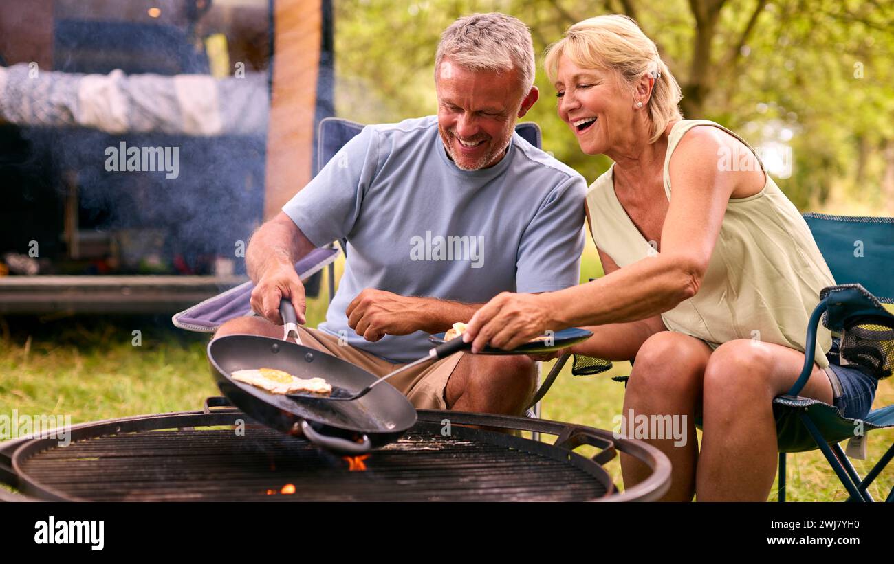 Senior Couple Camping In Countryside With RV Cooking Bacon And Eggs For ...