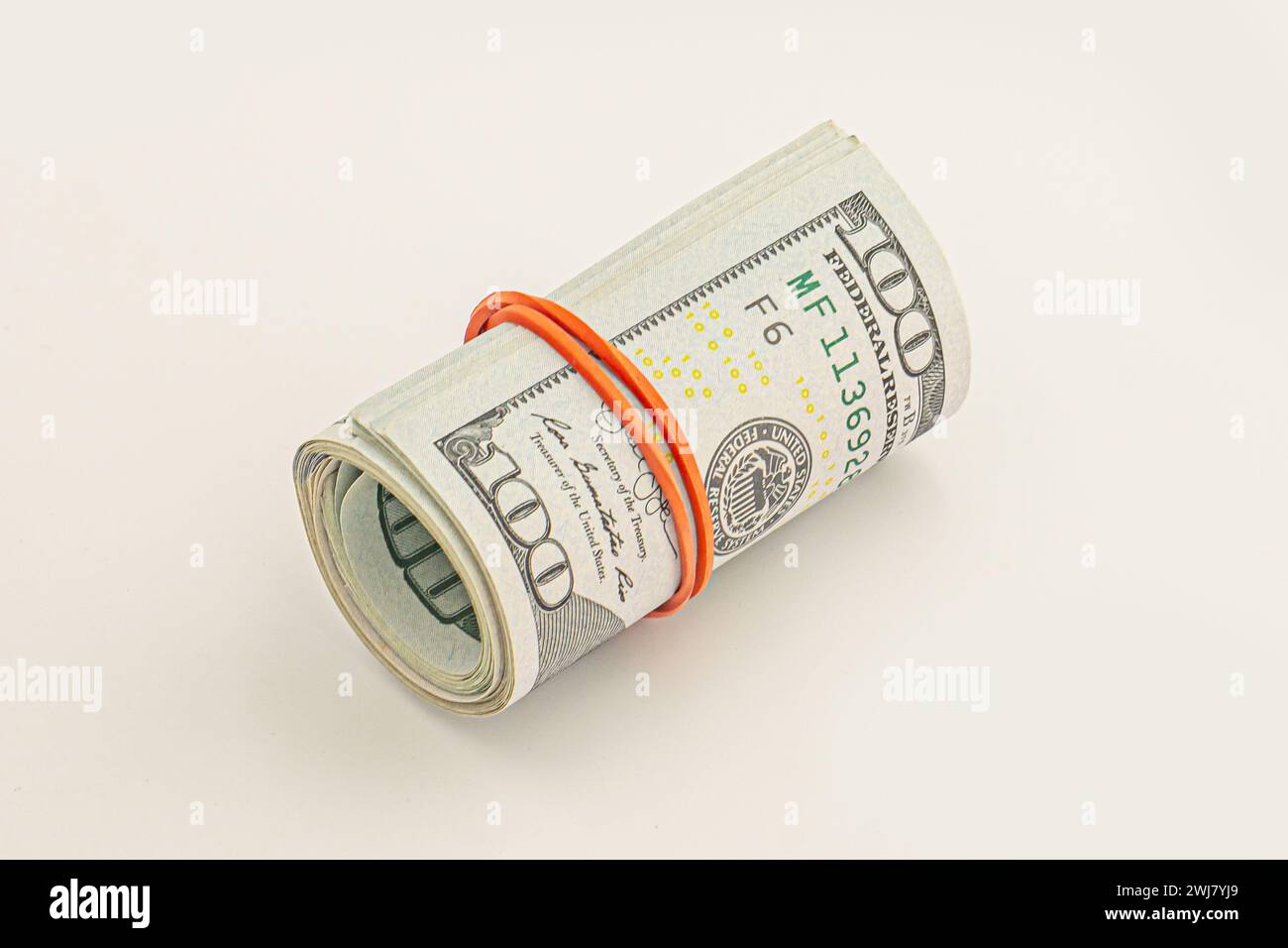 100 dollar bills on a roll isolated on white background. Rolled up ...