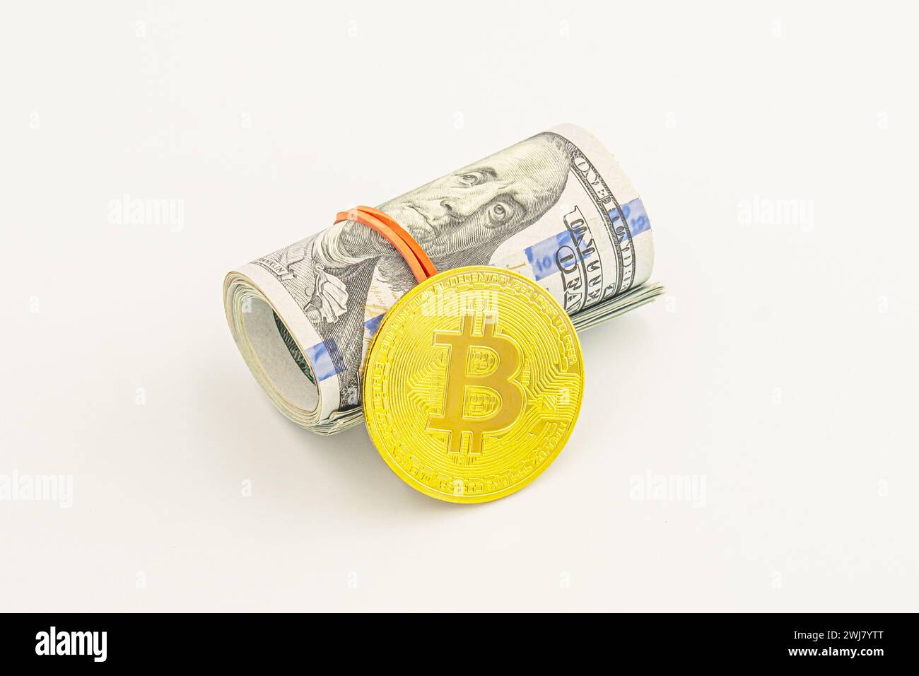 bitcoin BTC coin and roll of dollar bills banknotes white background ...