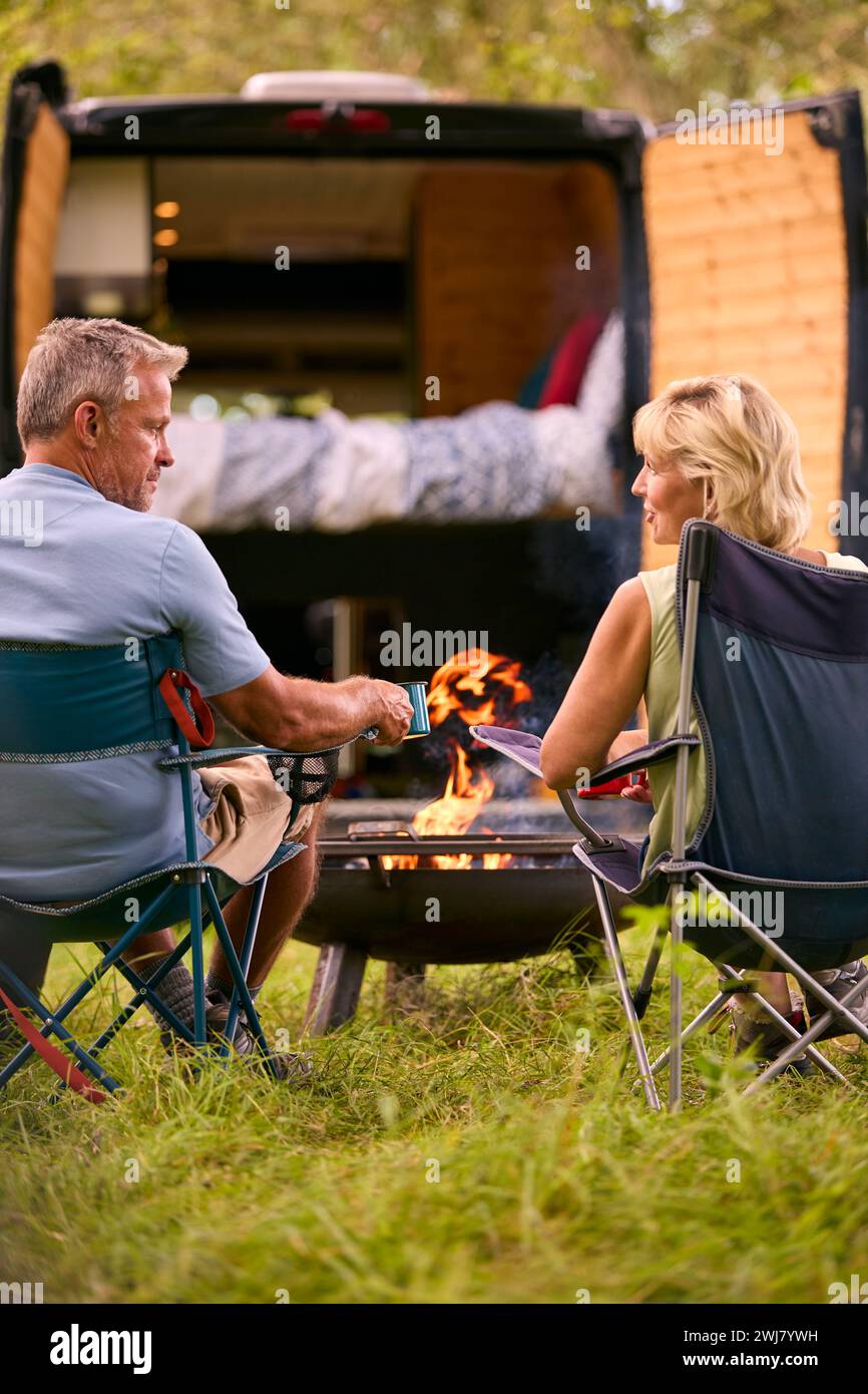 Rear View Of Senior Couple Camping In Countryside With RV Drinking ...