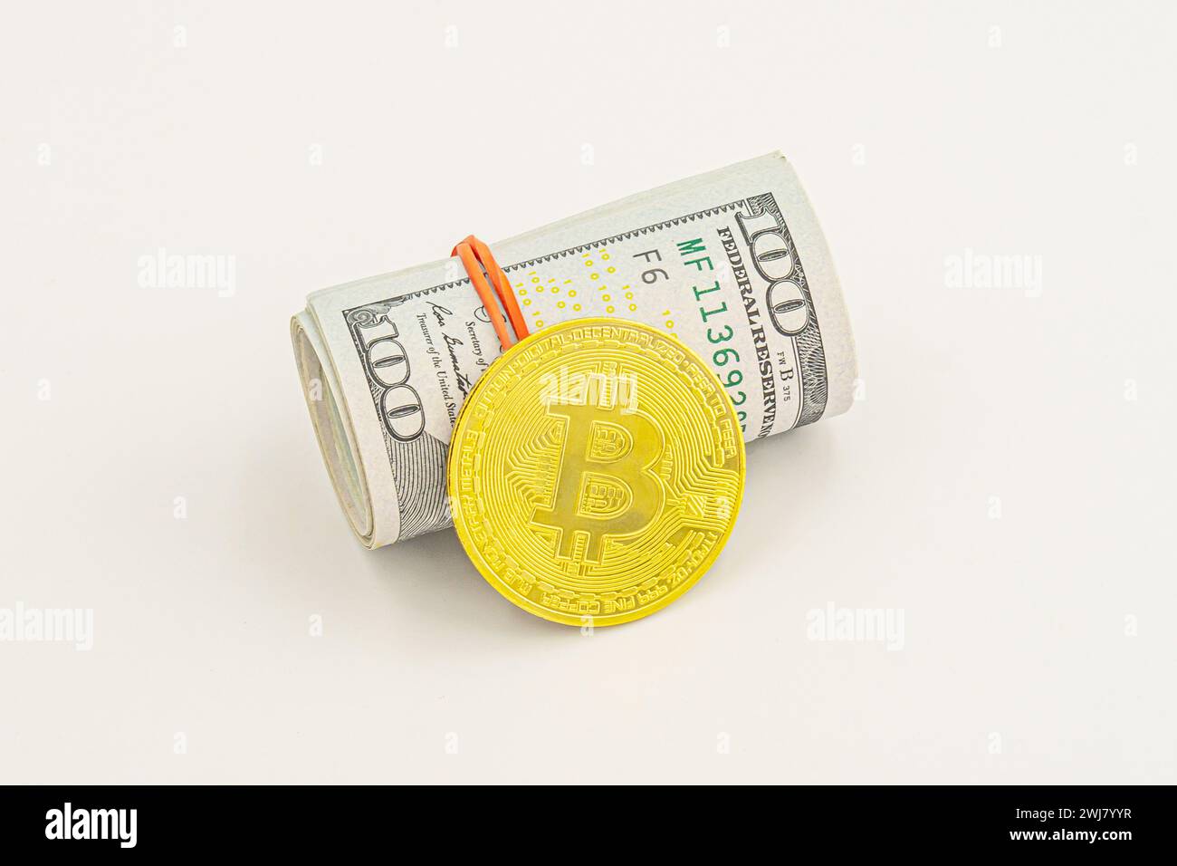 bitcoin BTC coin and roll of dollar bills banknotes white background ...