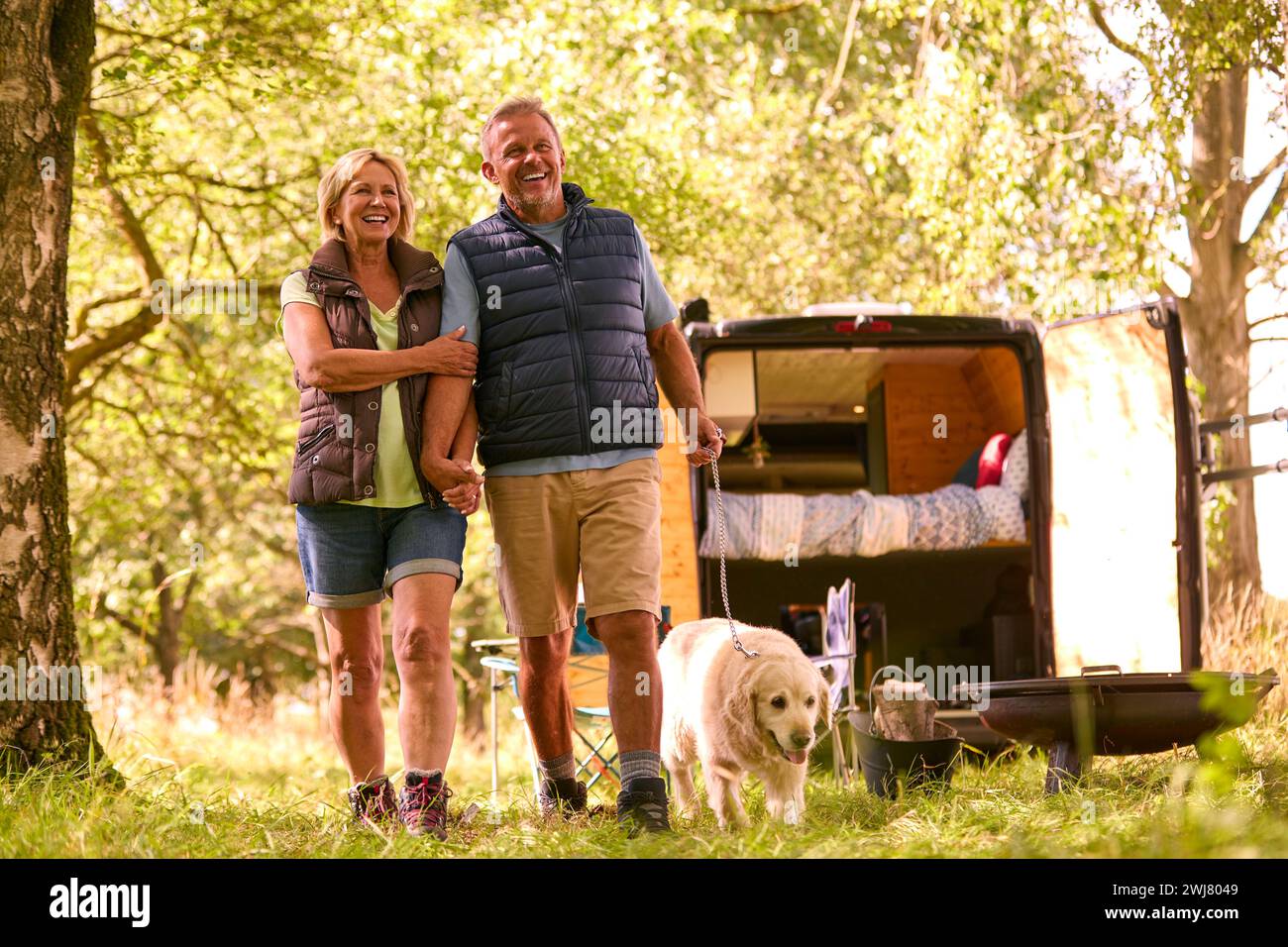 Senior Couple Camping In Countryside With RV Taking Labrador Dog For A ...