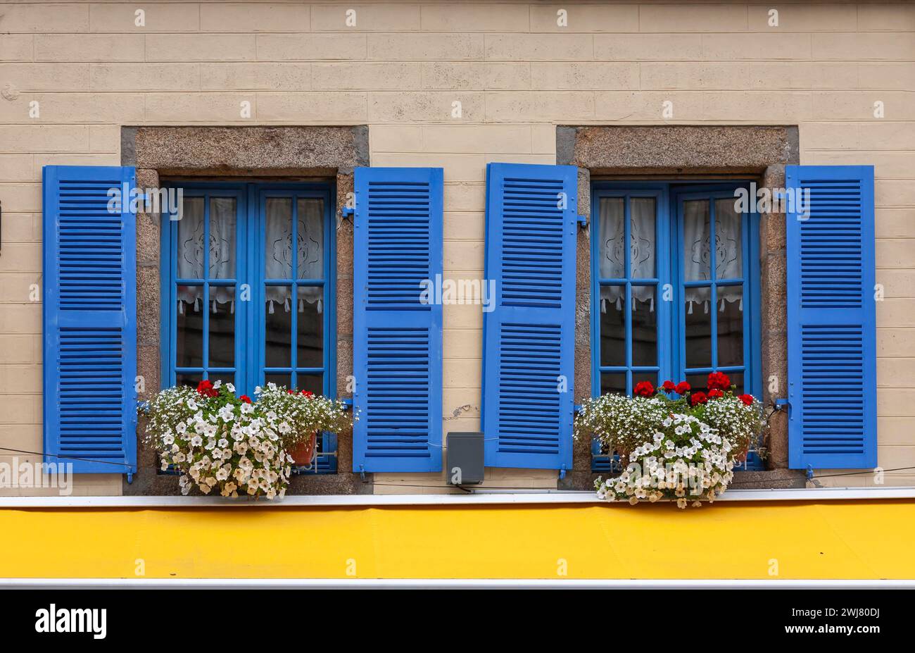 House facade with two windows, blue window frames and blue shutters ...