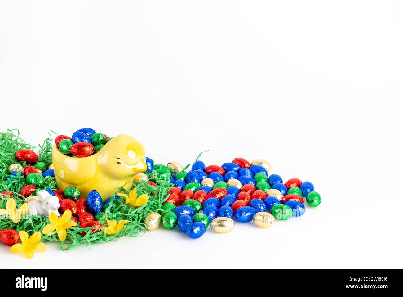 Chocolate eggs and a decorative chick surrounded by artificial grass as ...