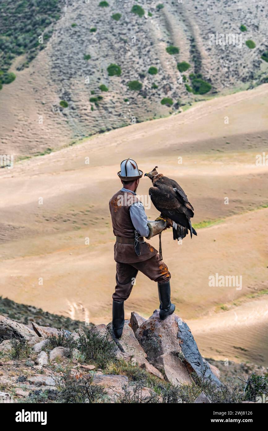 Traditional Kyrgyz eagle hunter hunting in the mountains in a dry ...