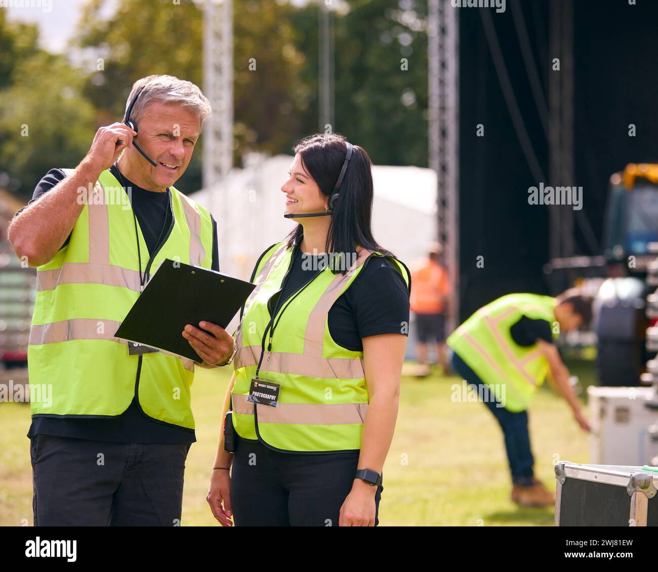 Production Team Talking On Headsets Setting Up Outdoor Stage For Music ...