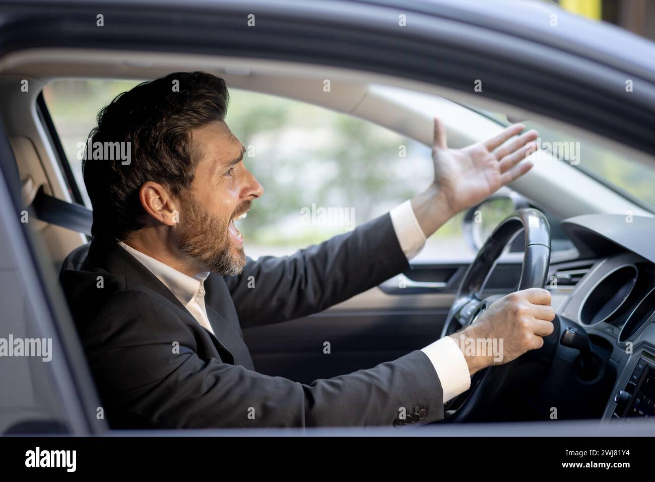 Close-up photo of angry young businessman in suit driving car and ...