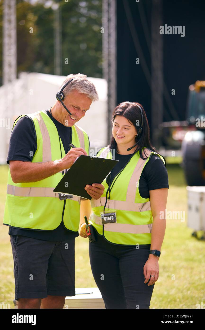 Male And Female Production Team With Headsets Setting Up Outdoor Stage ...